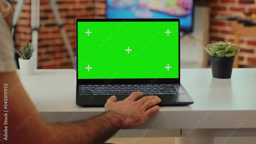 Male employee working with laptop and greenscreen template on display, looking at isolated ...