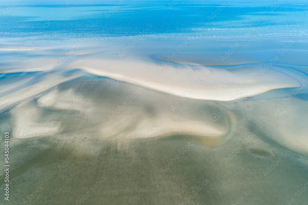 Aerial view of coastline and sandbar patterns in shallow blue water ...