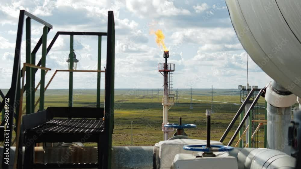 GAS FLARE burning on distant STACK behind METAL PLATFORM at industrial ...