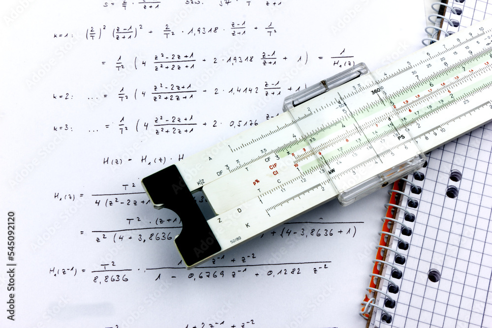 vintage slide rule being used for calculation with technical formula on ...