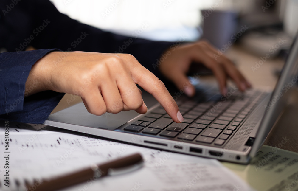 Woman types on the notebook. Desk with documents and business reports ...