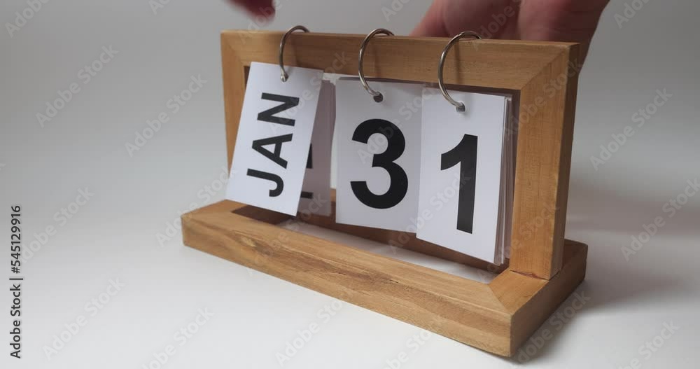 Man's hands turn over the paper pendant calendar on the marble table ...