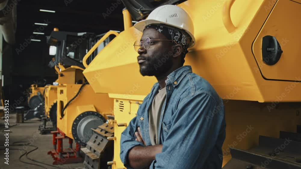 Medium portrait of young Black man in denim shirt and hard hat posing ...