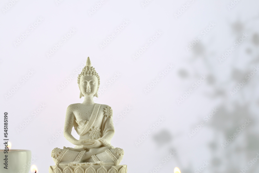 Buddhism composition with white Buddha statue and candles on a white ...