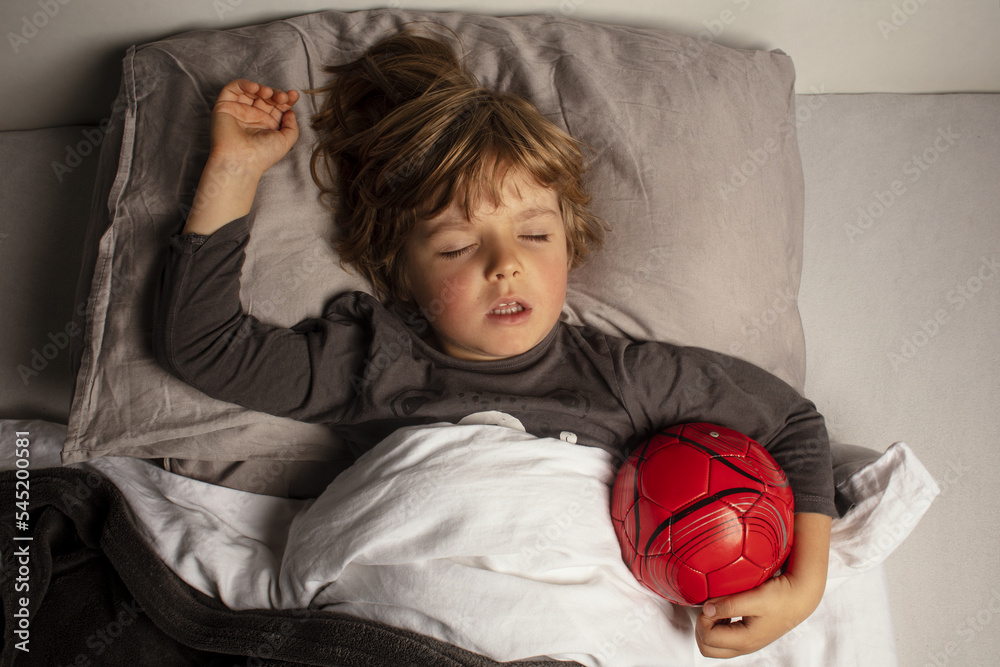 Healthy child, sweetest blonde toddler boy sleeping in a football ball ...