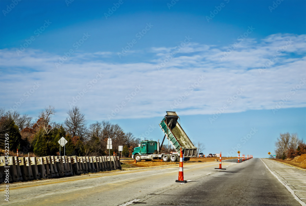 Road Construction - Dump truck dumping gravel where highway is being ...
