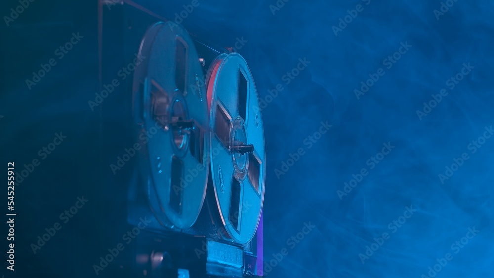 Poster Reel to reel tape recorder on studio background with blue light ...