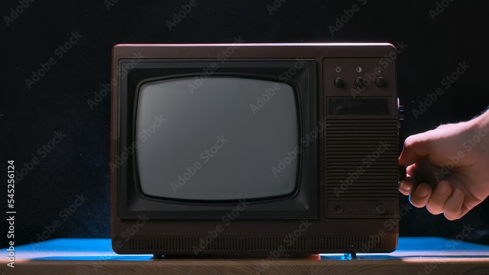 Man turning knob on an old retro TV on black studio background. Vintage ...