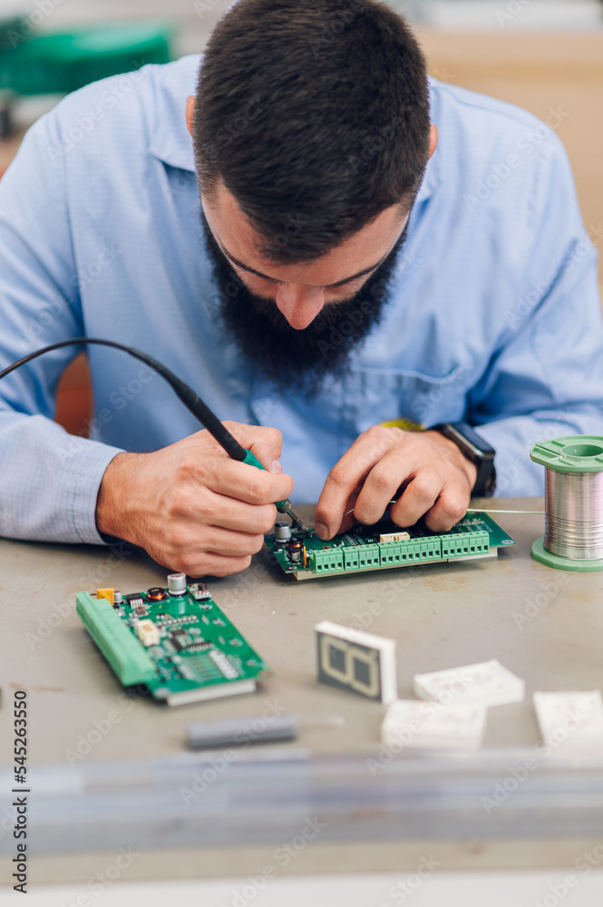 Poster Electronics engineer working in a workshop with tin soldering ...