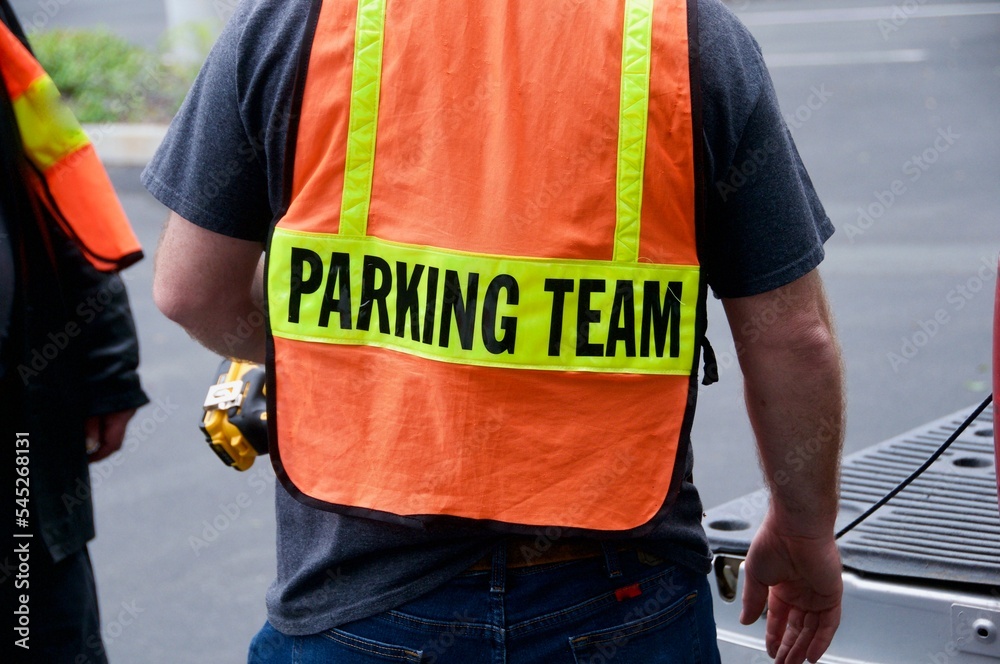 Parking lot attendant wearing bright orange and yellow safety vest ...