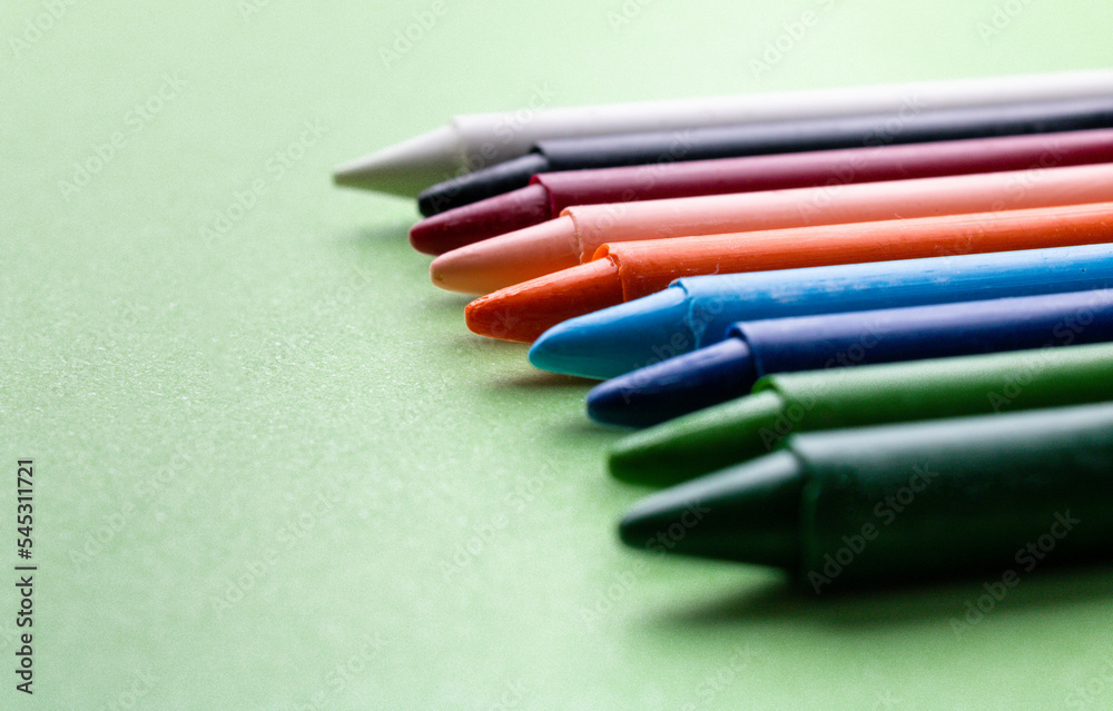 Set of crayons with different colors on a bright green background ...