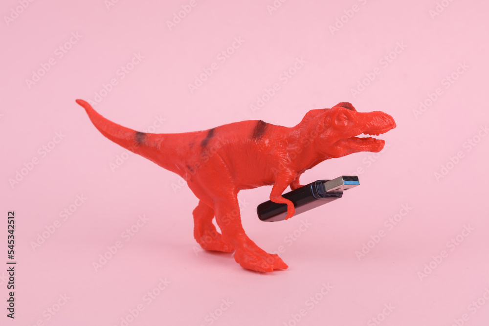 Toy dinosaur tyrannosaurus rex with usb flesh drive on pink background ...