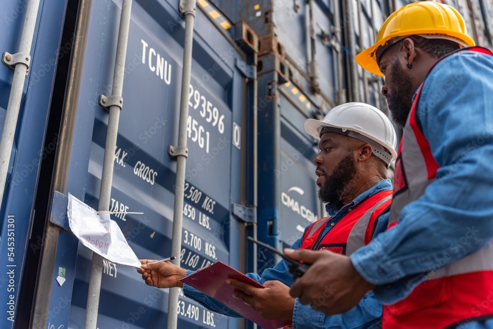 Two black african male professional engineers inspecting a container in ...