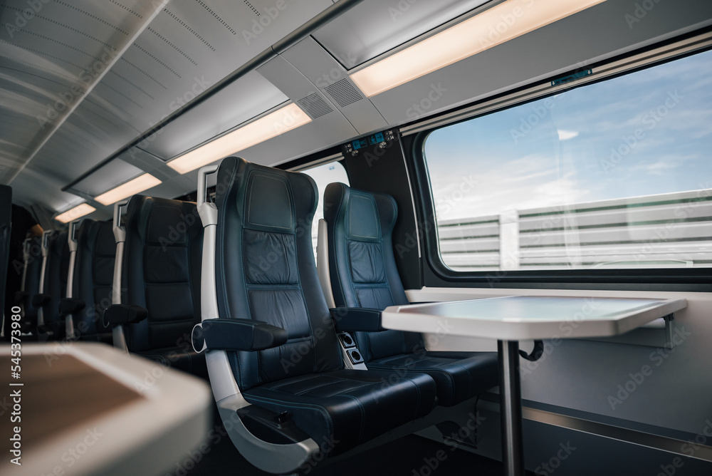 Table and empty seats in modern illuminated passenger intercity train ...