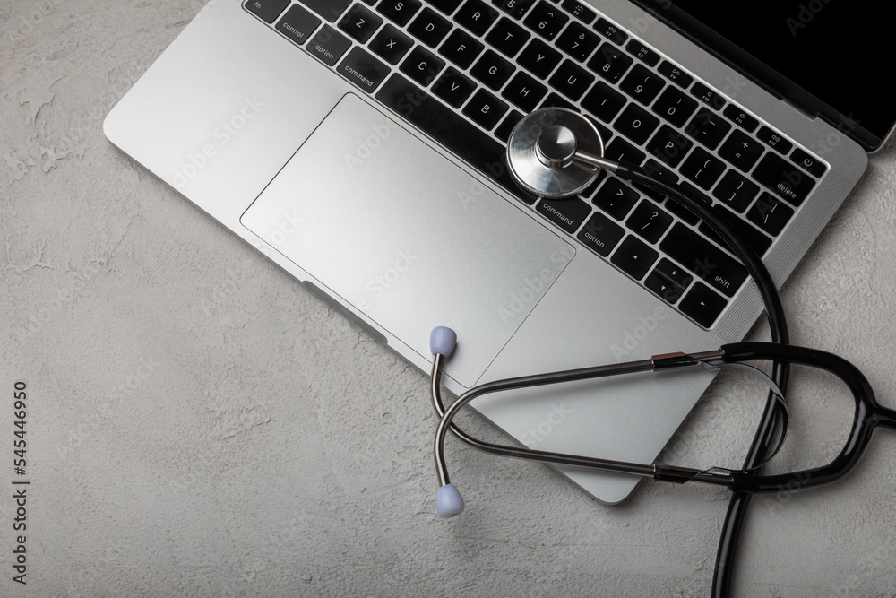 Laptop computer with stethoscope keyboard on black background. Modern ...