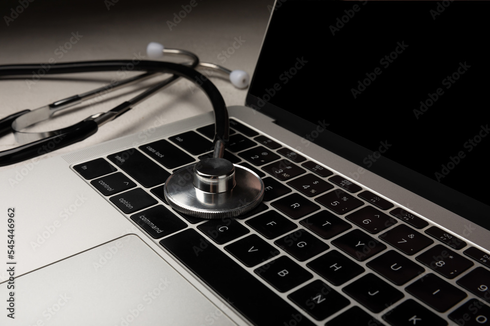 Laptop computer with stethoscope keyboard on black background. Modern ...