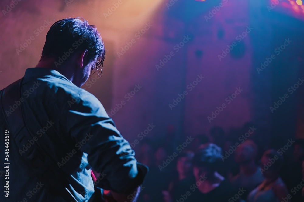 Backside view of a musician guy on the stage performing in front of the ...