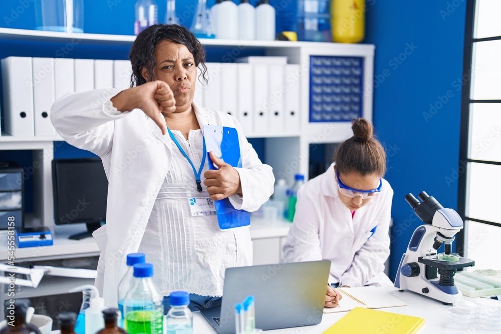 Mother and young daughter working at scientist laboratory with angry ...