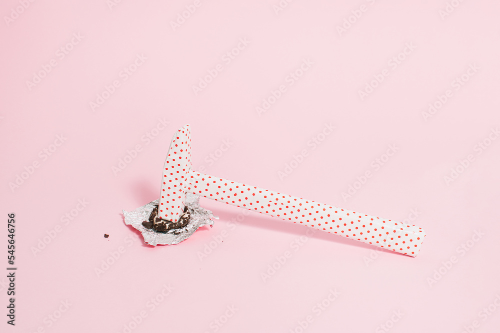 Hammer wrapped in dotted paper breaks the chocolate on bright pink ...