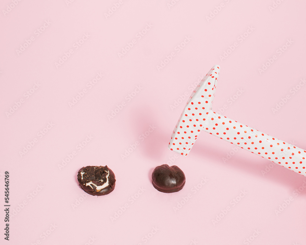 Hammer wrapped in dotted paper breaks the chocolate on bright pink ...