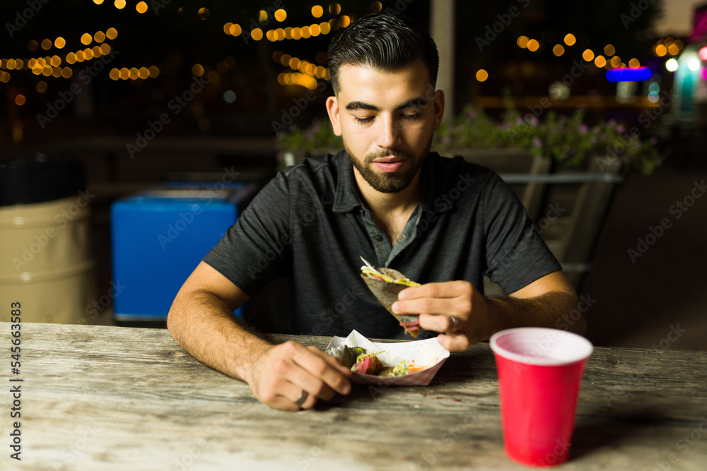 Latin young man eating mexican tacos at the food cart Stock Photo ...