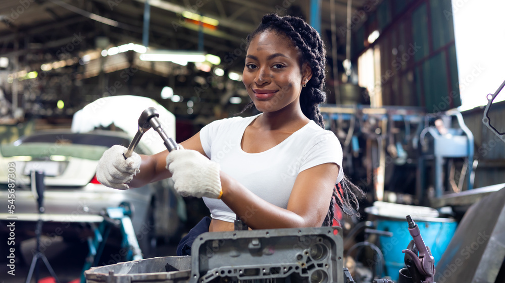 African young female car mechanic checking and fixing car engine at ...