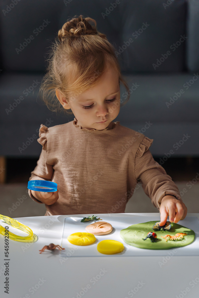A little girl playing with toy insects. Educational game Bug Fossils ...