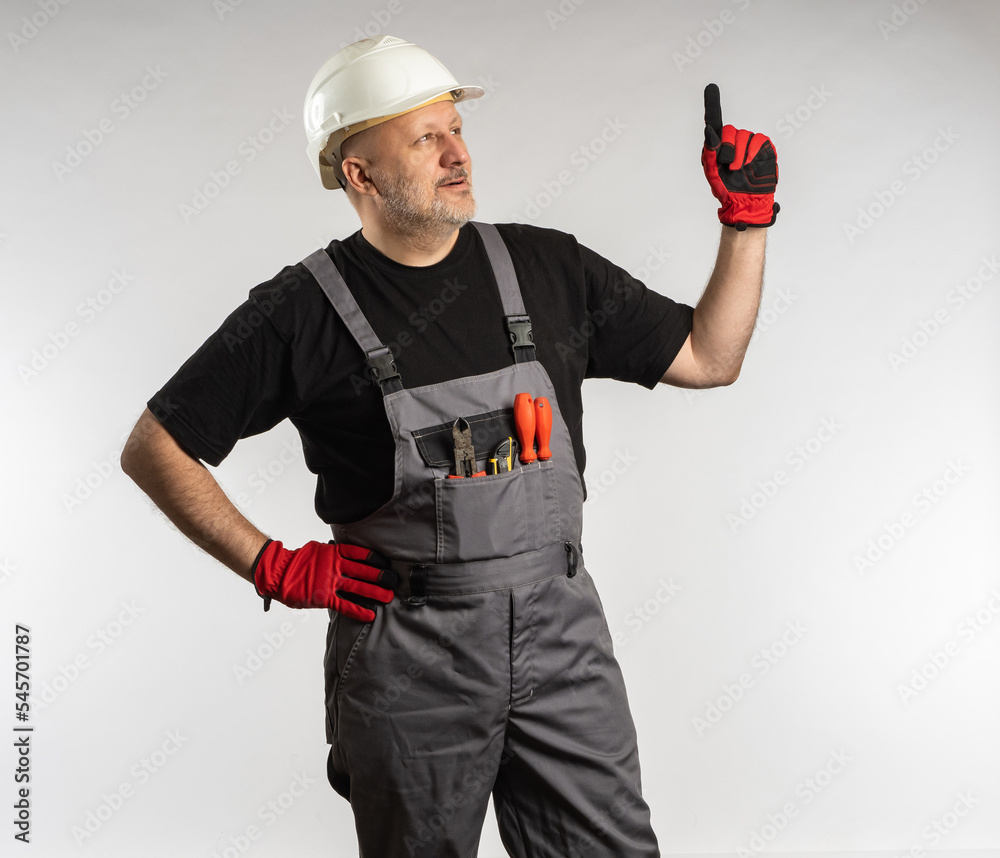 Man builder came up with idea. Guy in builders uniform stands on gray ...