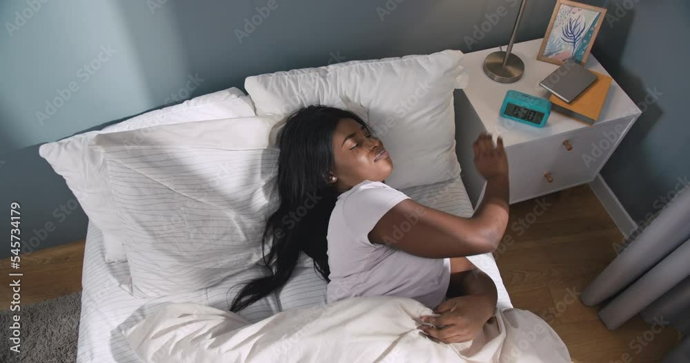 Young attractive African-American female model sleeping in white bed ...