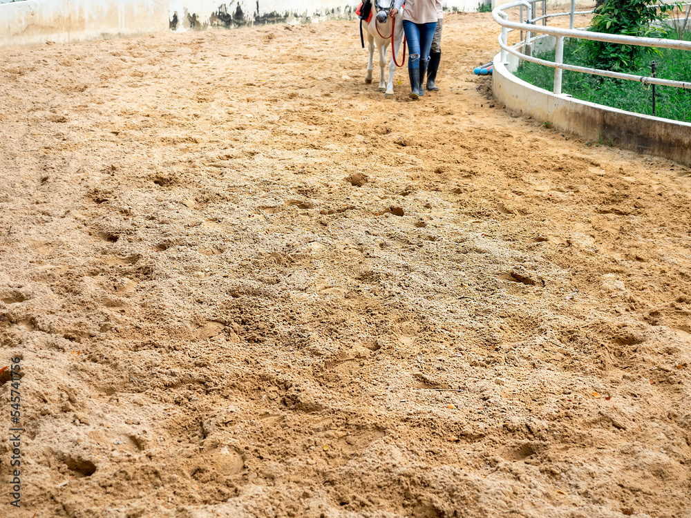 Outdoor space of sand on horse race track with horseman leading a horse ...