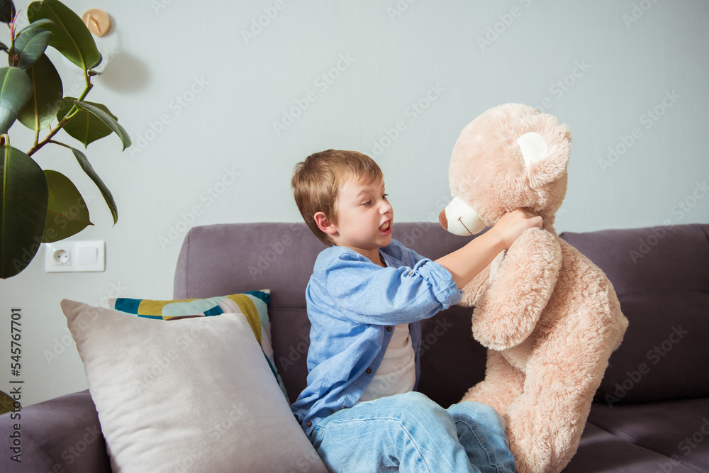 Child aggression. Irritated little boy suffocating a teddy bear. Bad ...