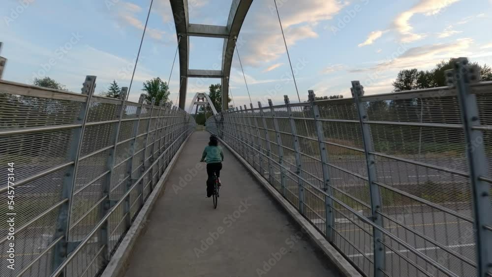 Woman on Bicycle riding across Pedestrian bridge over Trans Canada ...
