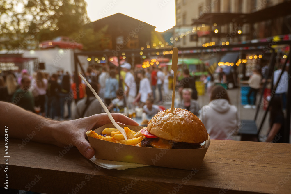 Man hands holding street food burger with french fries on craft paper ...