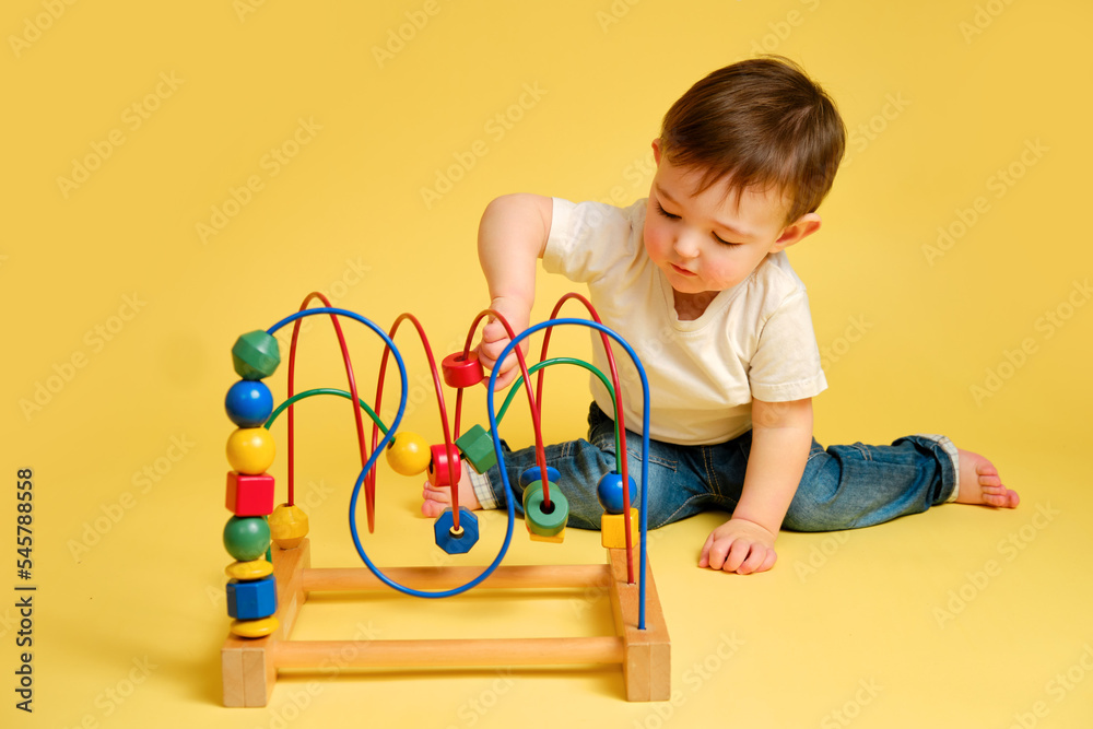 Toddler baby is playing logic educational games on a studio yellow ...