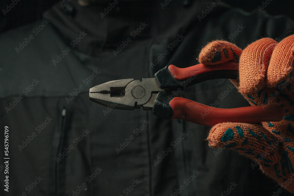 man's hand holding a black and red wire cutter plier open ready to cut ...