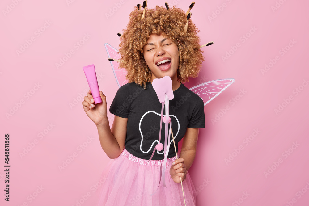 Overjoyed curly tooth fairy holds toothpaste wears black t shirt ...