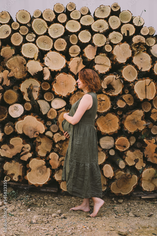 Beautiful pregnant woman near felled trees. Happily expecting a baby ...