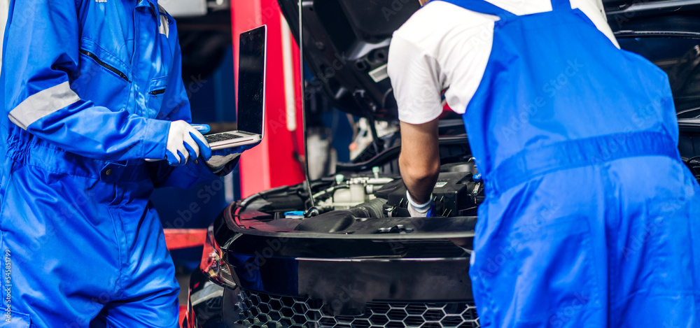 Professional car technician mechanic team in uniform use laptop work ...