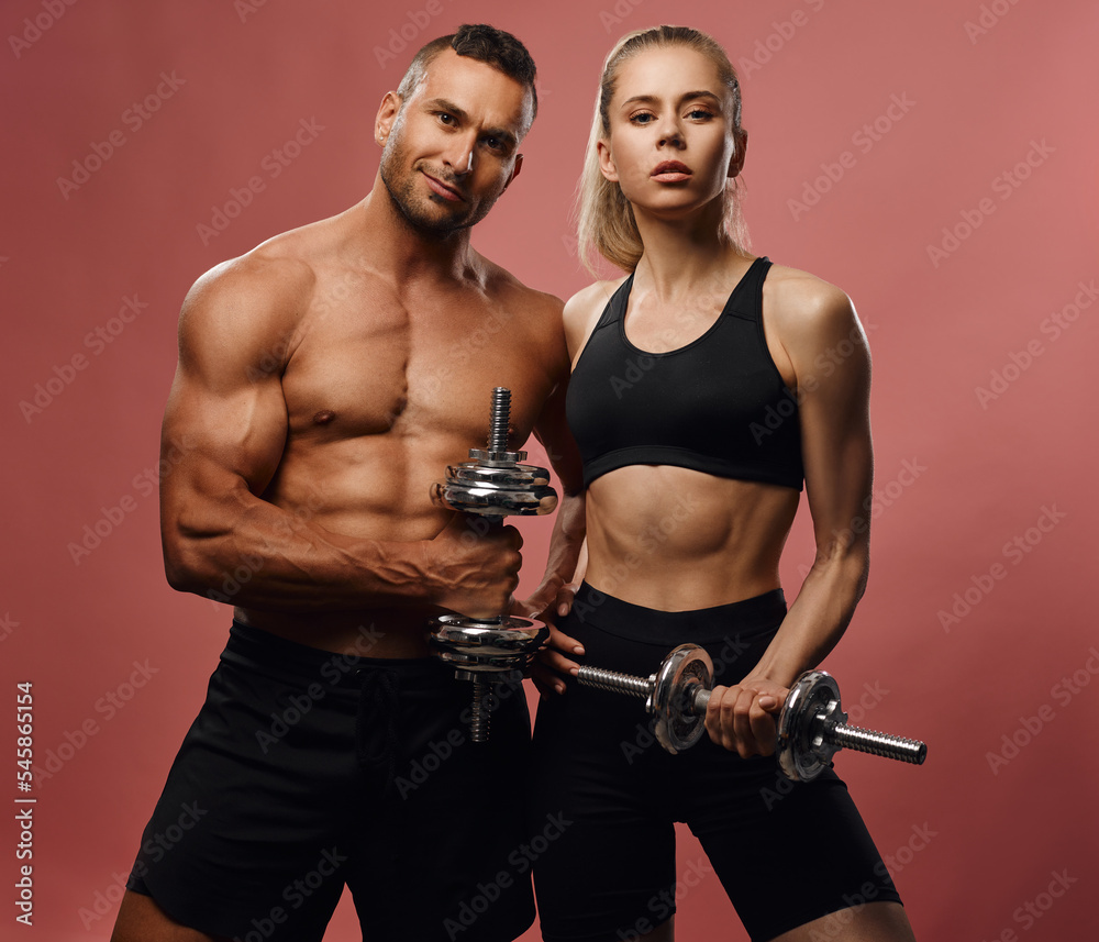 Fitness male and female models with equipment at pink background ...