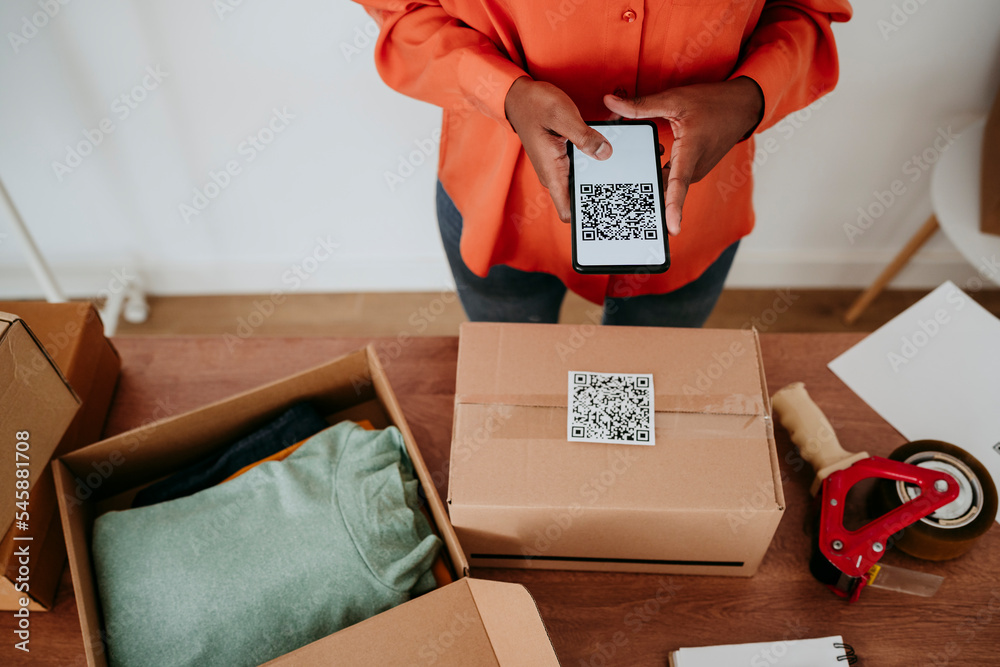Businesswoman scanning QR code on package at desk Stock Photo | Adobe Stock
