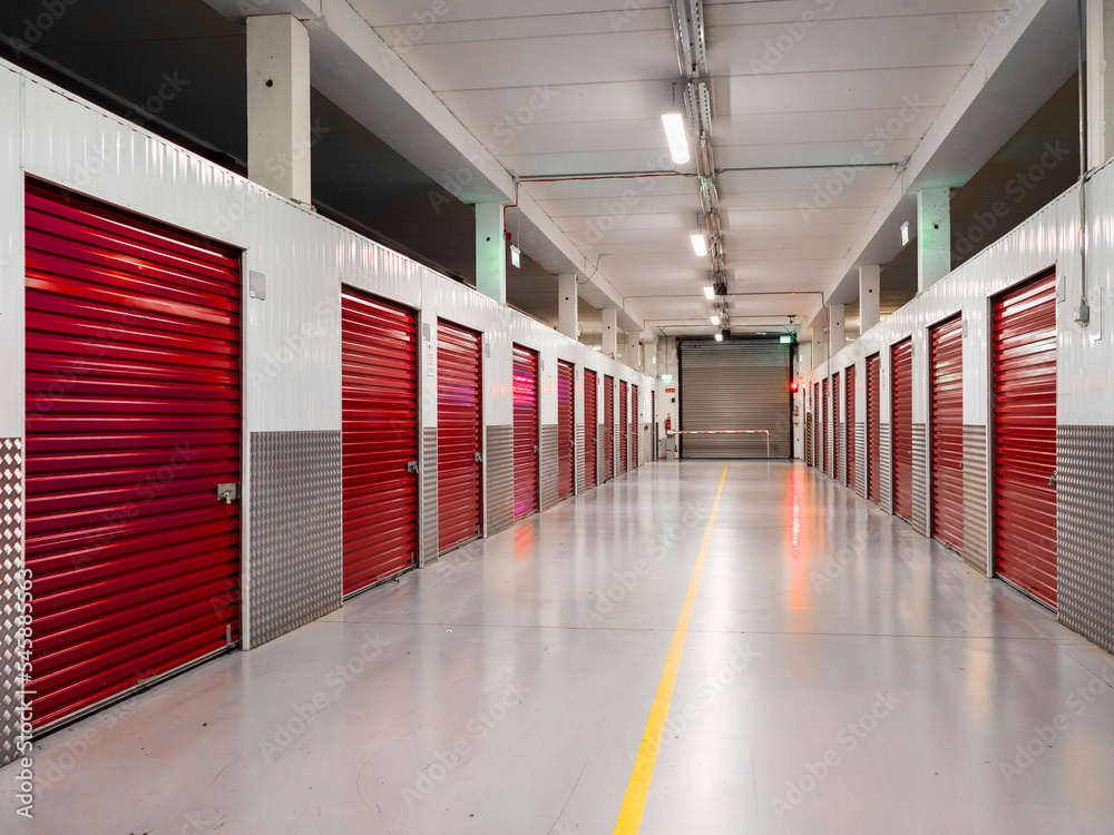 Long row of red color doors of self storage facility. Service to keep ...