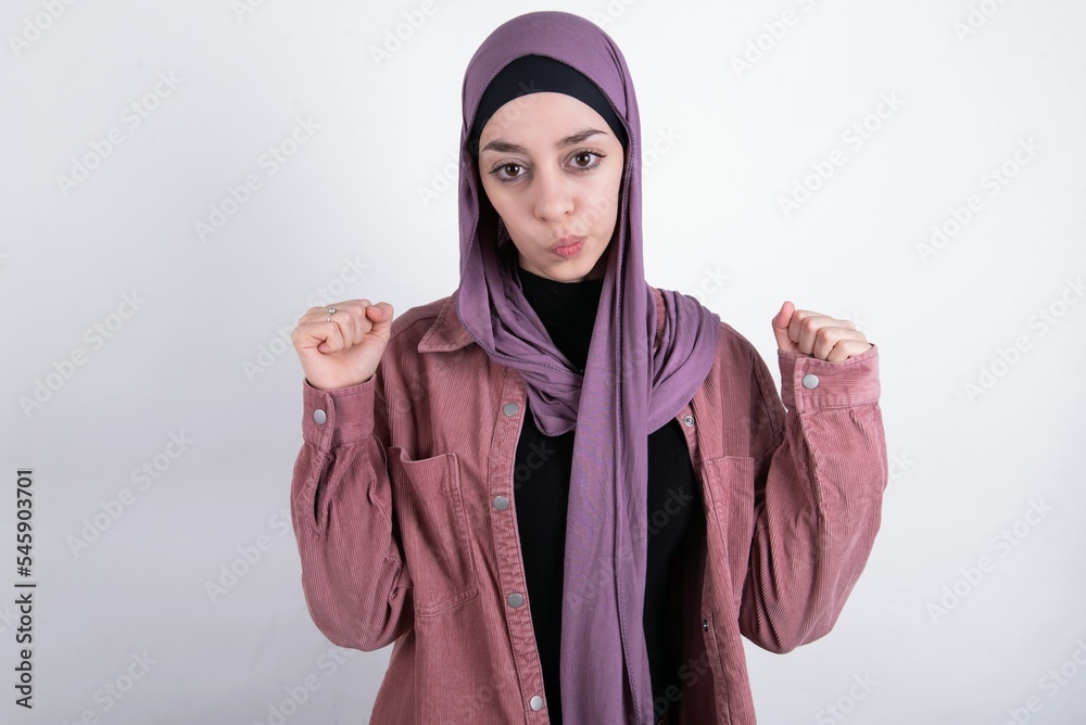 Irritated young beautiful muslim woman wearing hijab and pink jacket ...