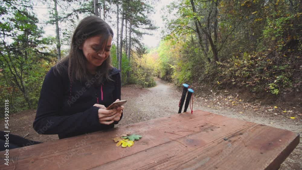 Hiking girl sitting on a wooden bench in rest area on dirtroad or trail ...