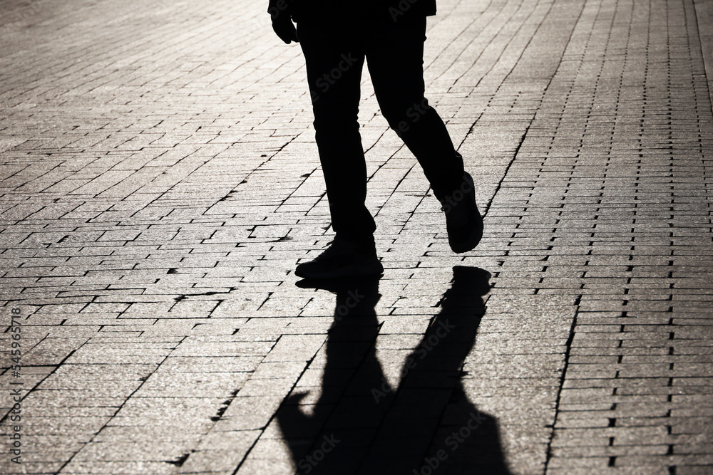 Black silhouette and shadow of lonely man walking on a street. Male ...