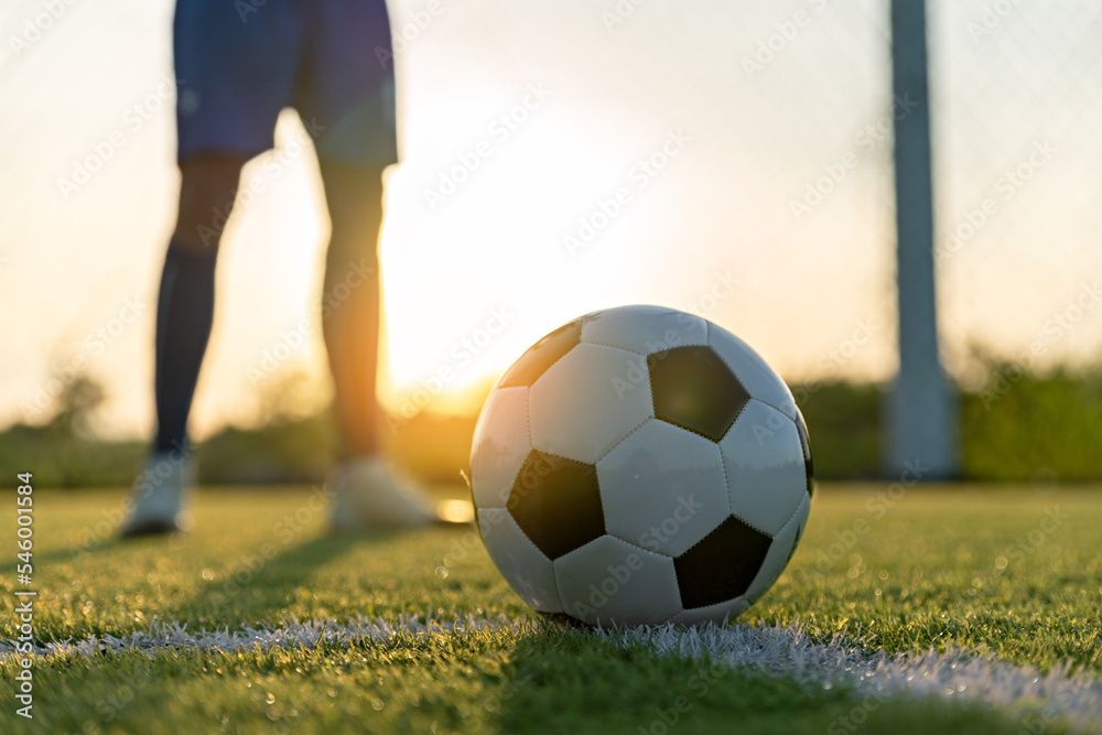 Athlete standing with ball on football field during sunrise, soccer ...