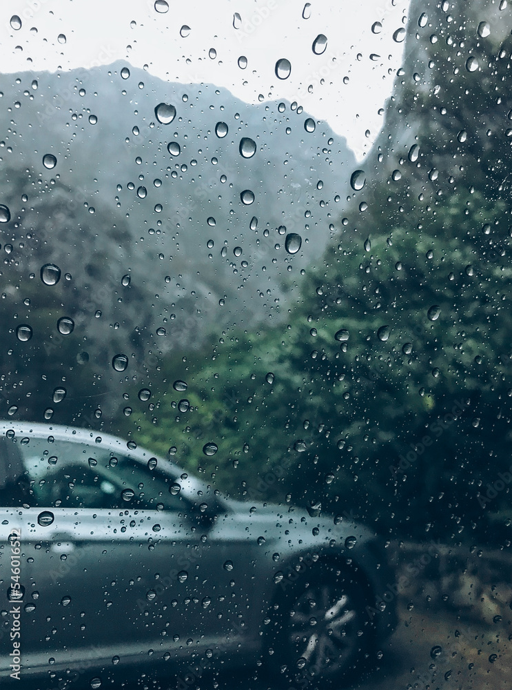 Raindrops on the clean car glass image with silver color car on the ...