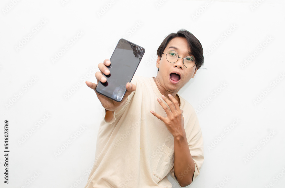 excited young asian man in beige tshirt holding and showing phone ...