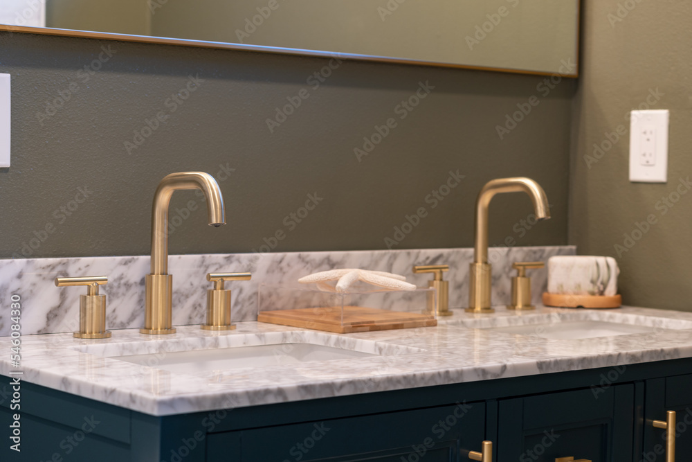 Modern bathroom vanity details of gold faucets and hardware with marble ...