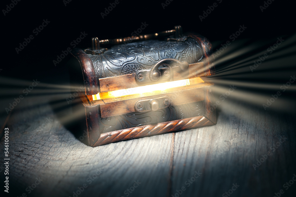 Glowing bright rays of light from an old, open wooden dark brown ...