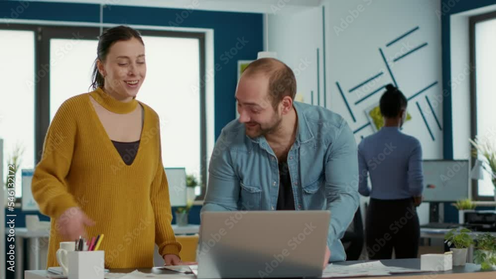 Smiling coworkers in office looking at laptop screen comparing business ...